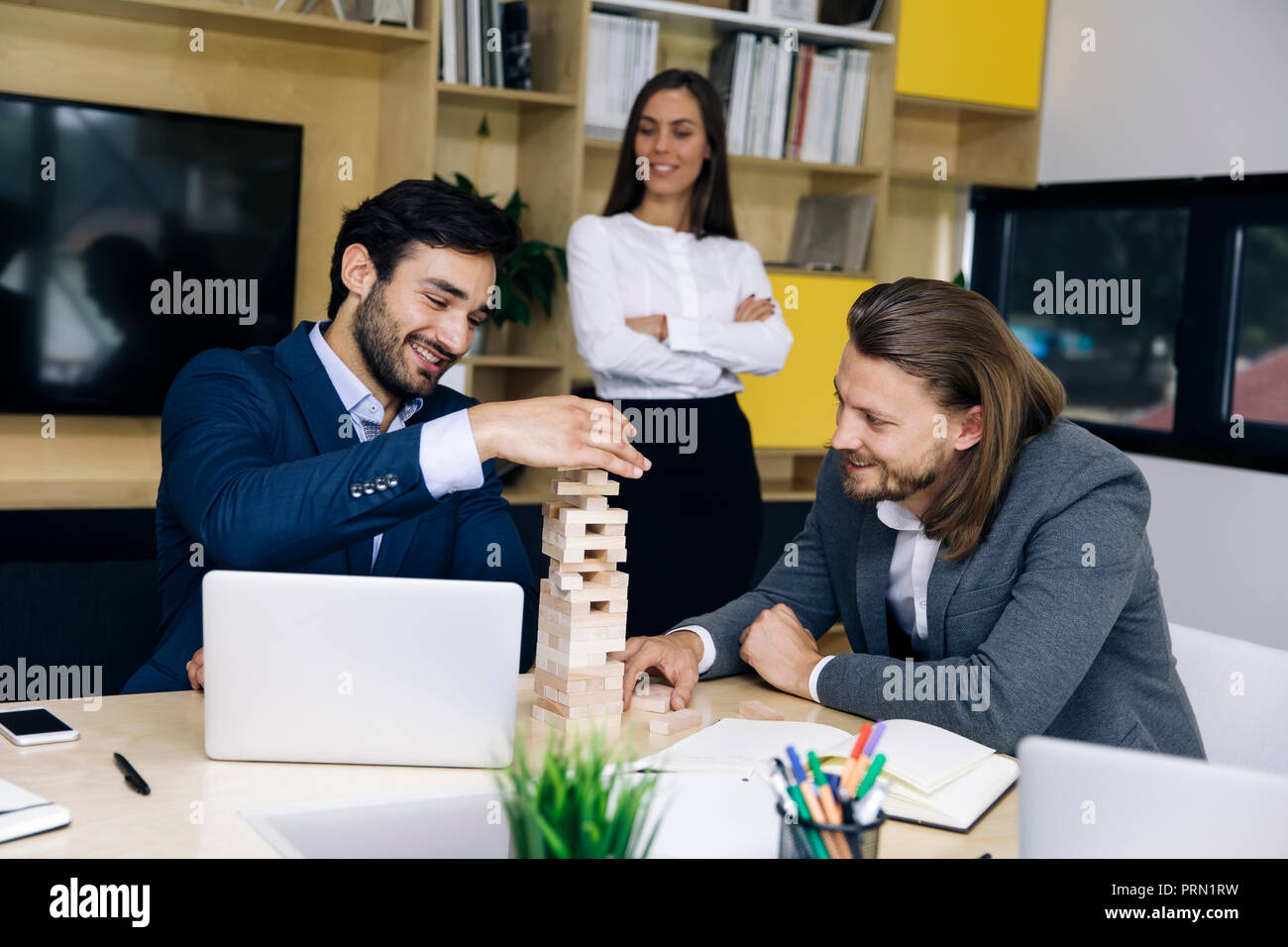 Team of young business people build a wooden construction in the office ...