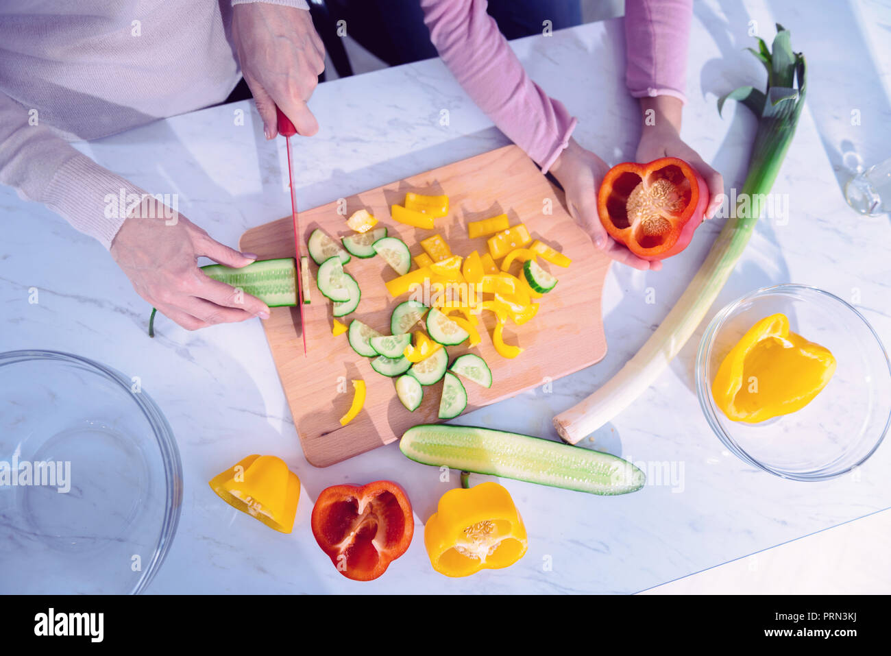 Two people cutting vegetables while being in the kitchen Stock Photo ...
