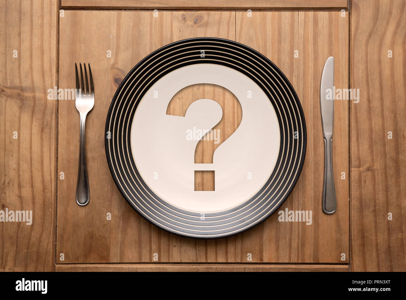 Question mark on plate with fork and knife on rustic wooden table in ...