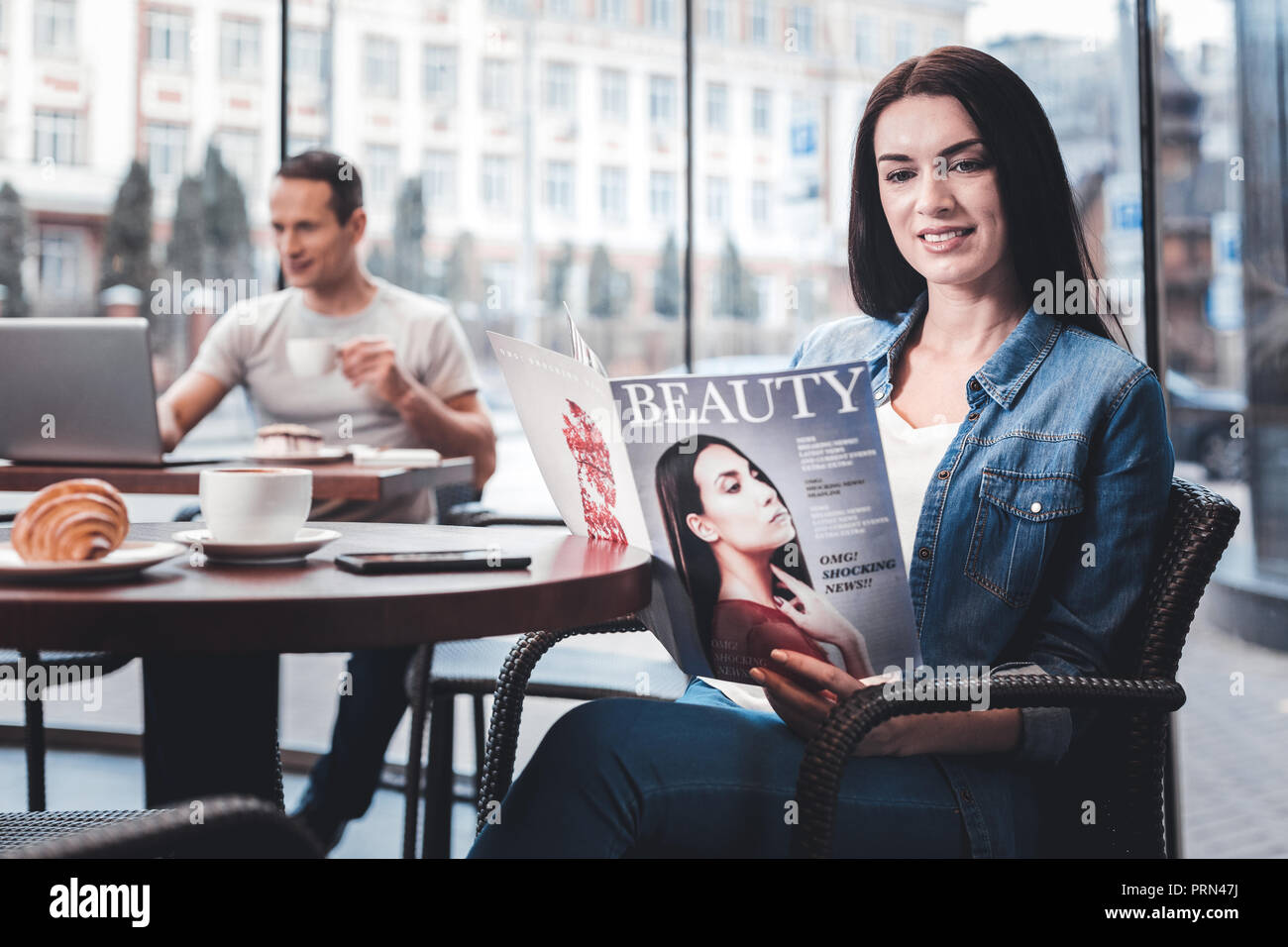 Relaxed girl reading while waiting for her friend Stock Photo - Alamy