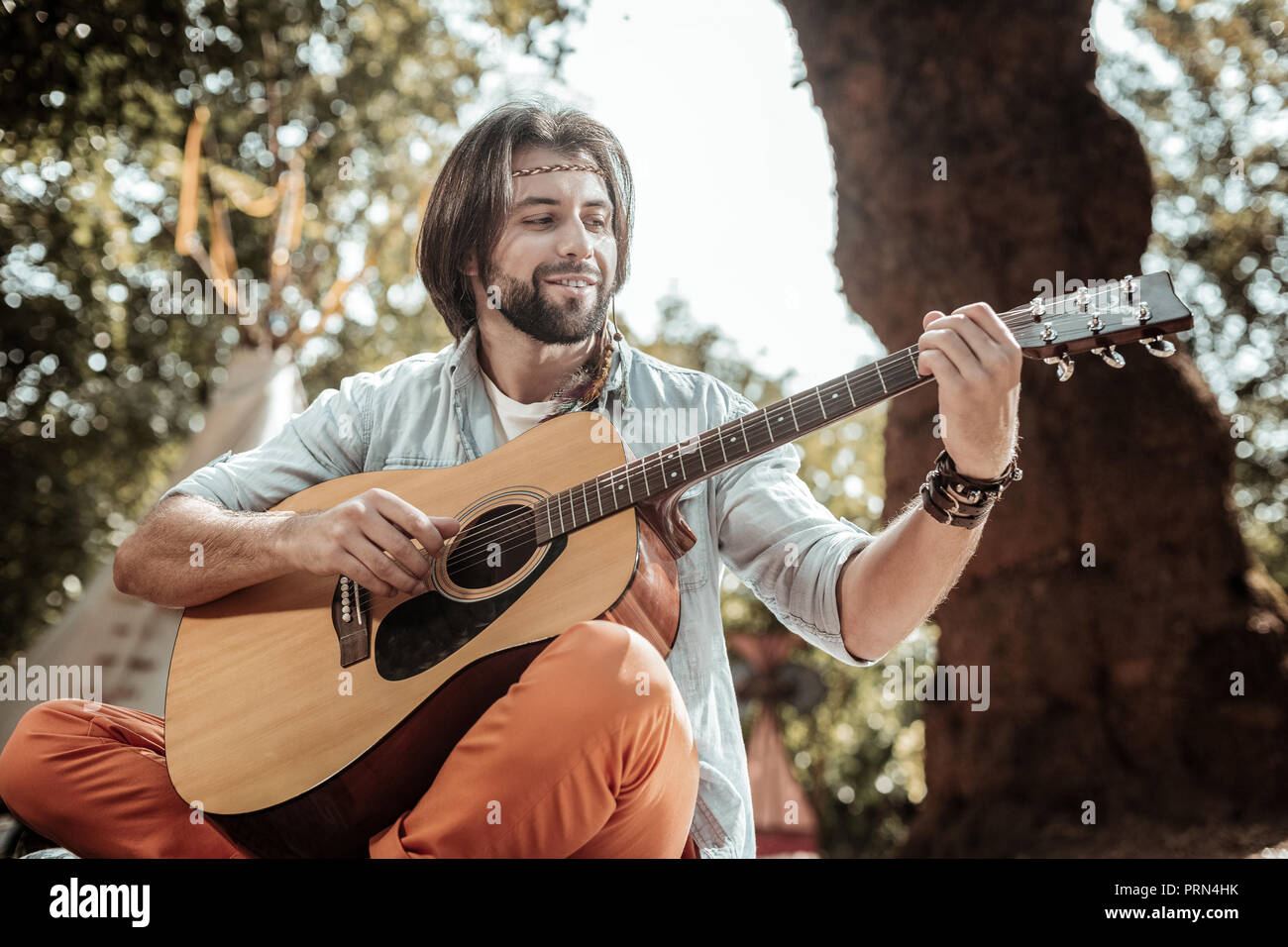 Smiling bearded man singing songs playing guitar Stock Photo - Alamy