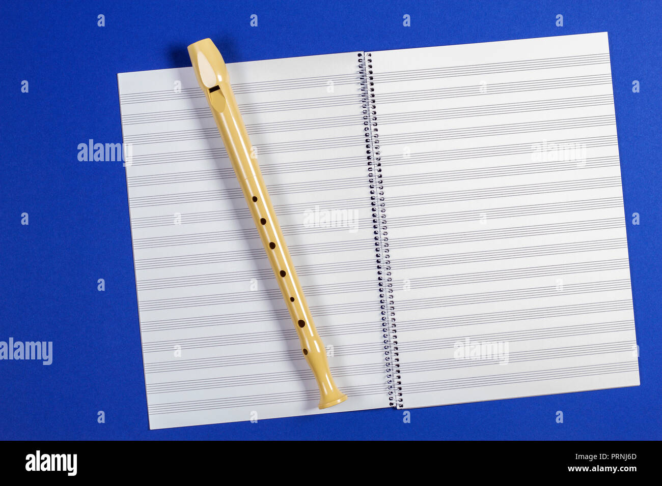Open exercise book with pentagrams and musical instrument flute on blue ...