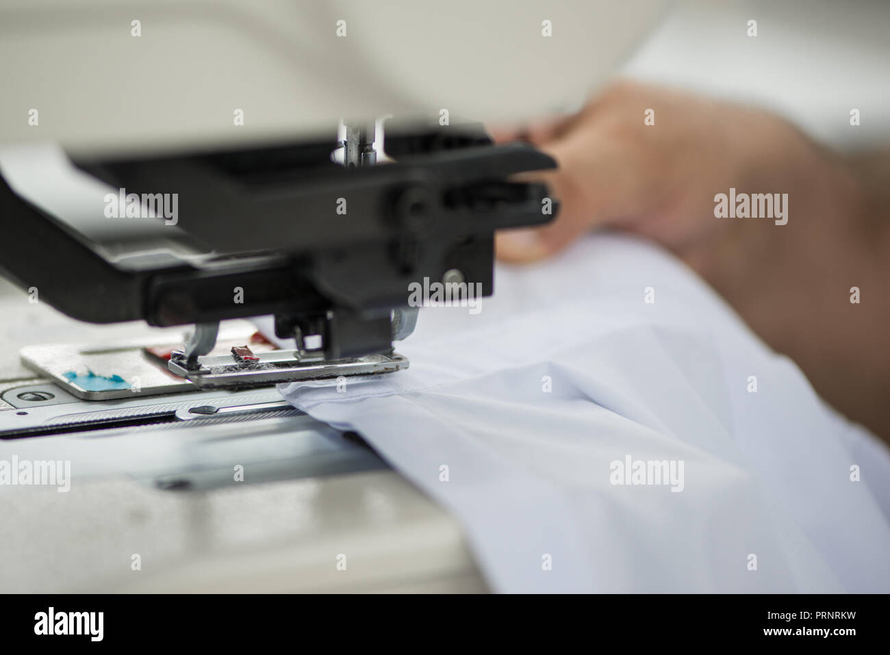 seamstress male on a sewing machine makes a shirt in the sewing ...