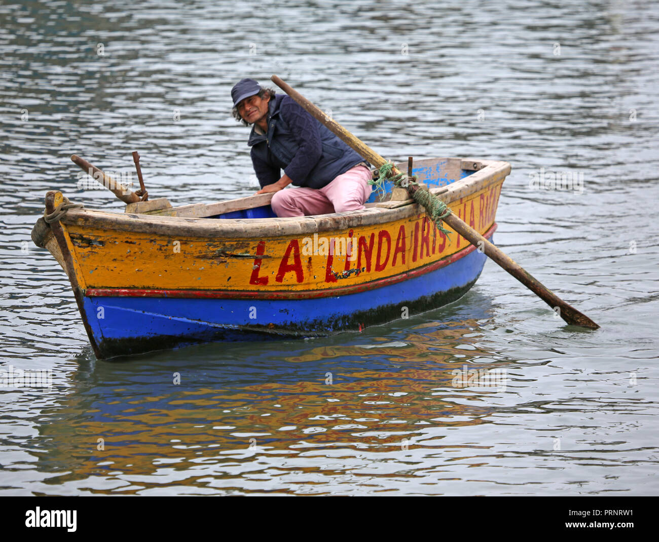 fisherman in blue and orange rowboat with ours in water Stock Photo - Alamy