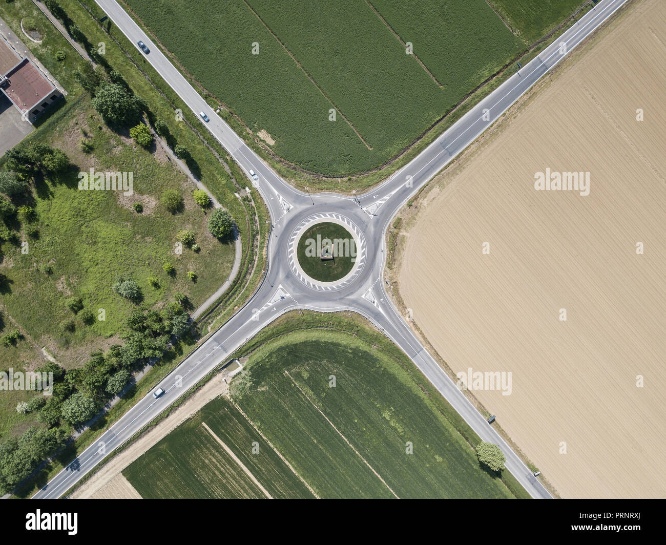 aerial view of four roads with roundabout surrounded with agro fields ...