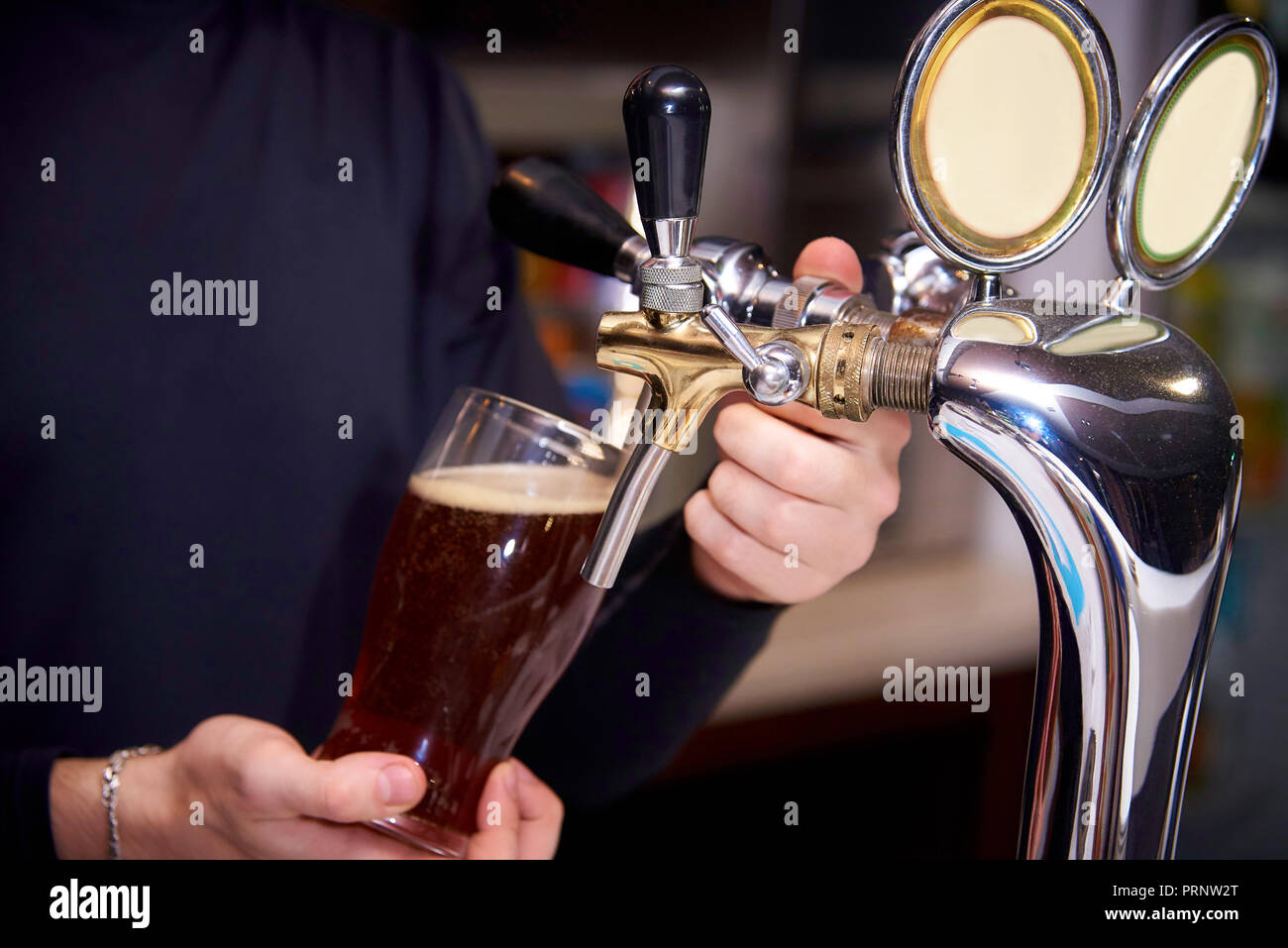 The barman pours beer from the tap into the glass Stock Photo - Alamy