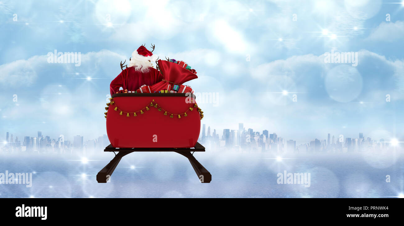 Composite image of rear view of santa claus riding on sled with gift ...