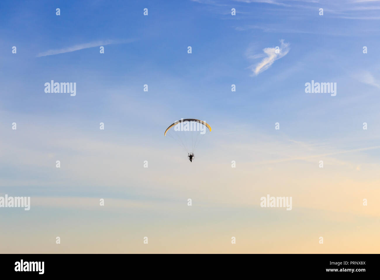 Single Powered paraglider with red and yellow canopy in blue sky and ...