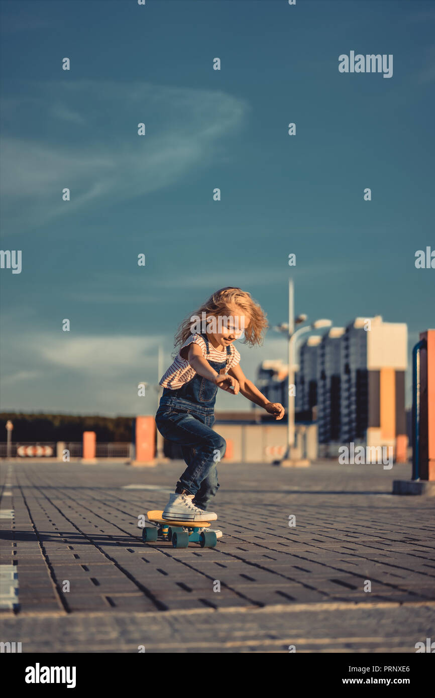 smiling little child riding on skateboard at parking lot Stock Photo ...