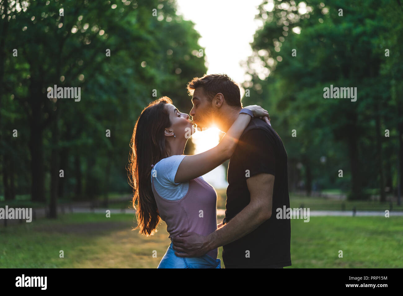 side view of young couple kissing each other against setting sun Stock ...