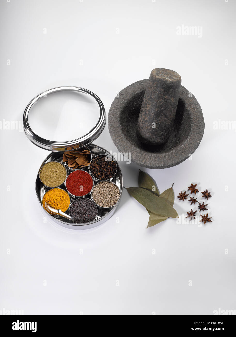 Stone grinder and pestle with stainless masala dabba on a white ...