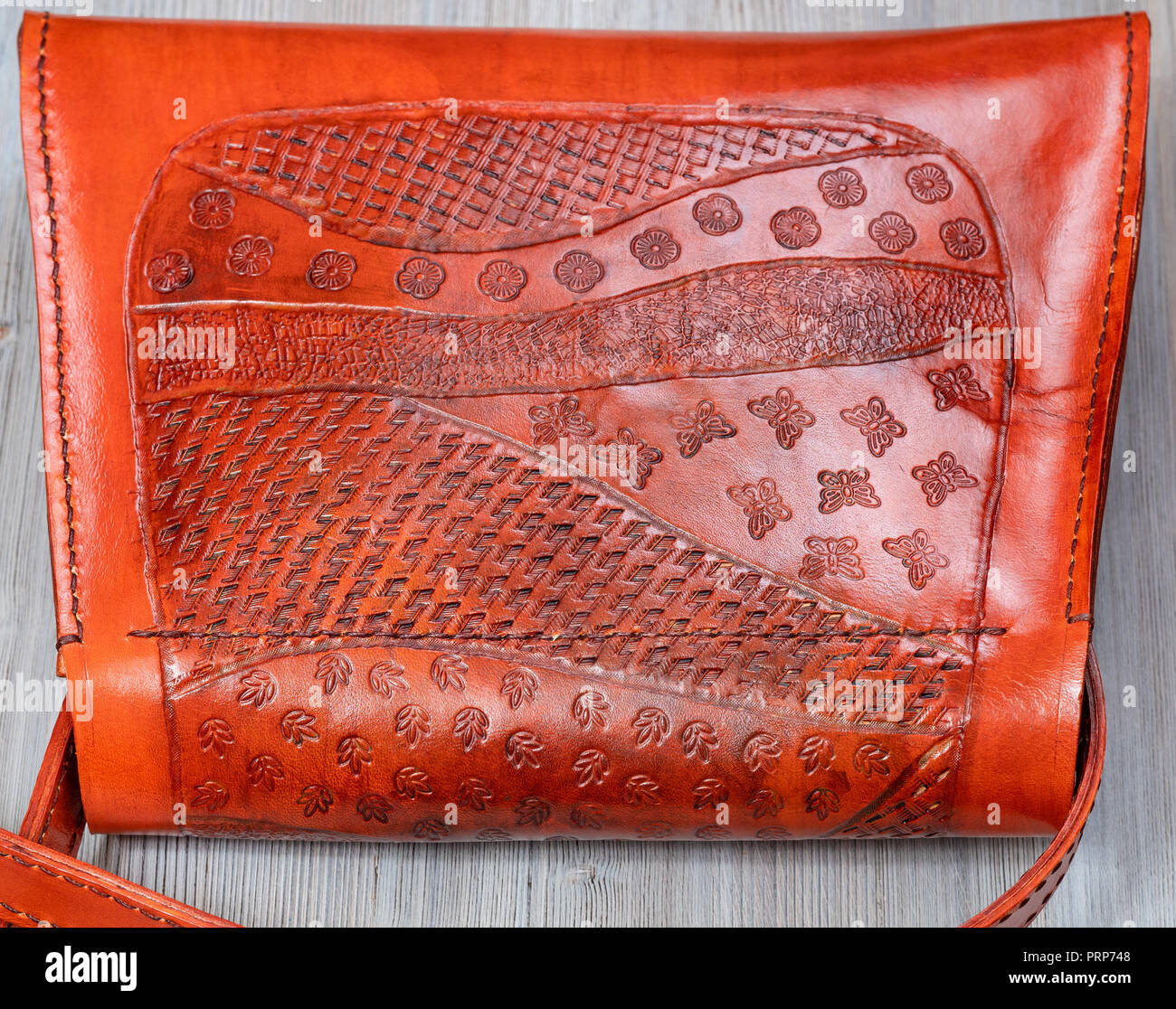 handmade embossed pattern on back side of orange colored leather ...