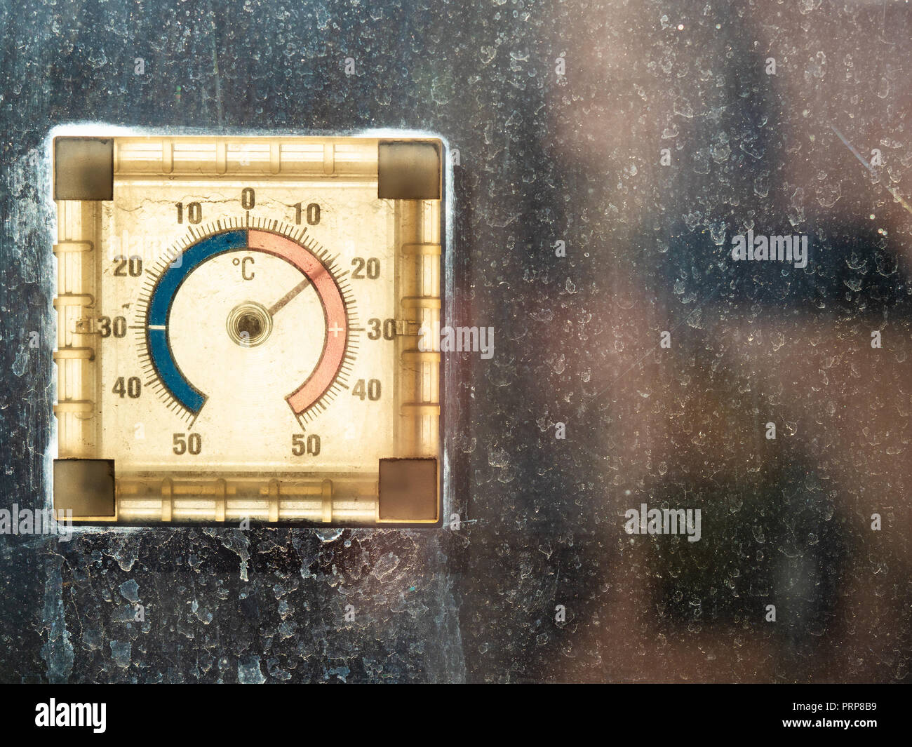 outdoor thermometer illuminated by sun close up on dirty window at home ...