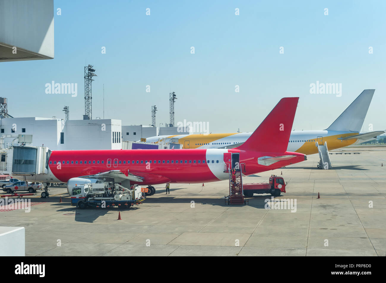 Loading airplanes with gangways and luggage carrying cars at runway of ...