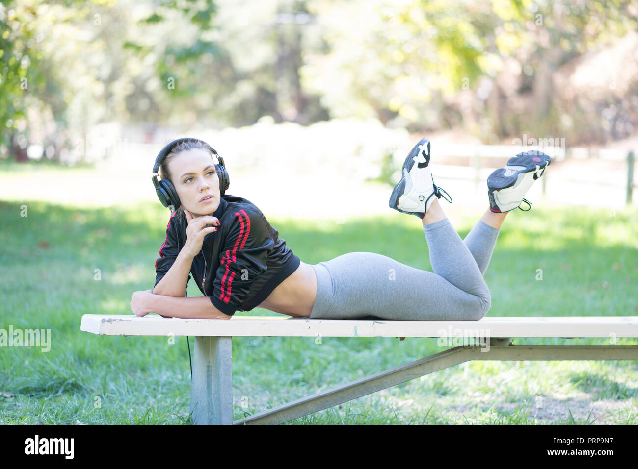 Female Model listening to music on headphones outdoors at the park ...