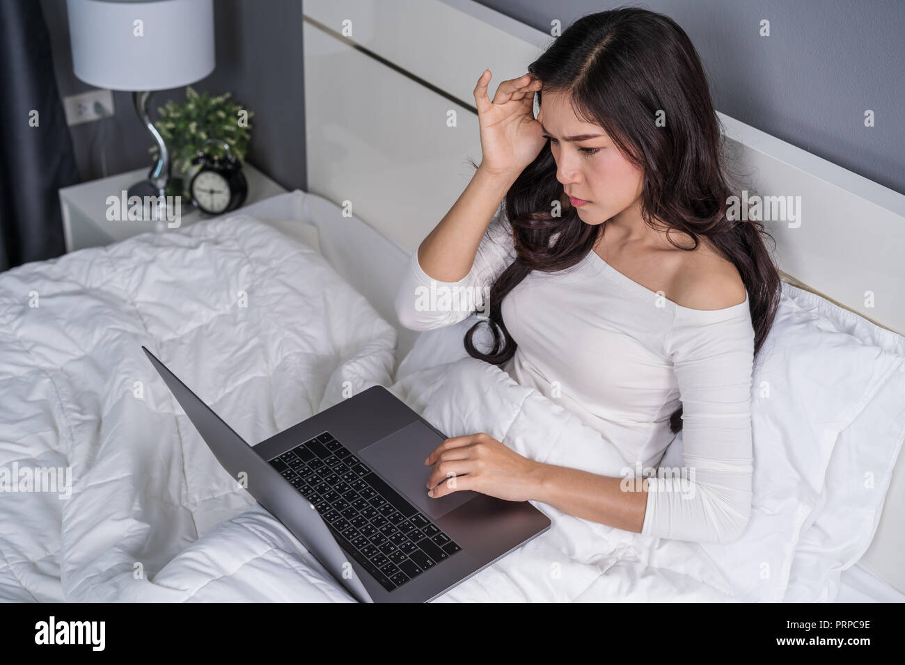 stressed woman using a laptop computer on bed Stock Photo - Alamy