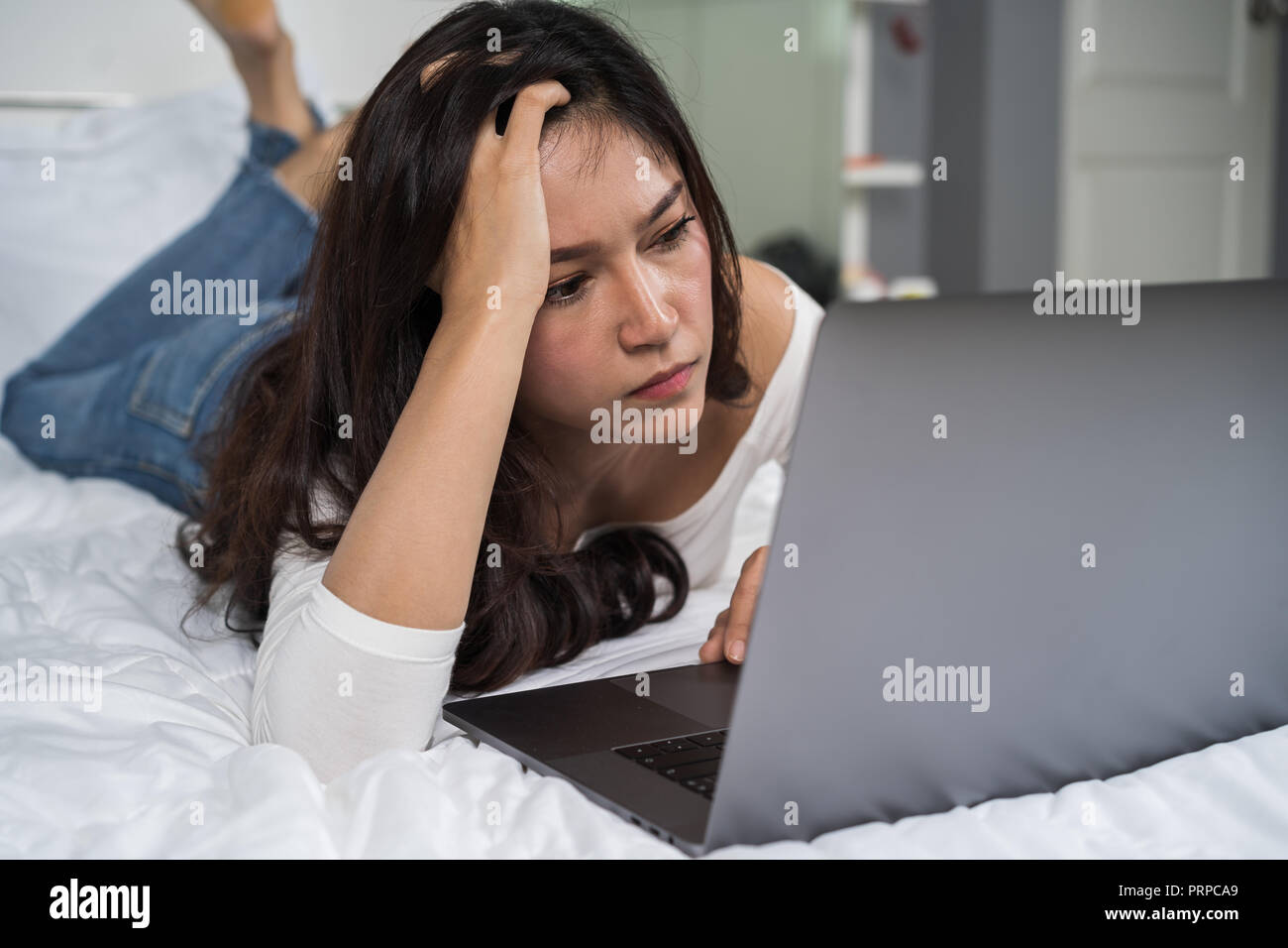 stressed woman using a laptop computer on bed Stock Photo - Alamy