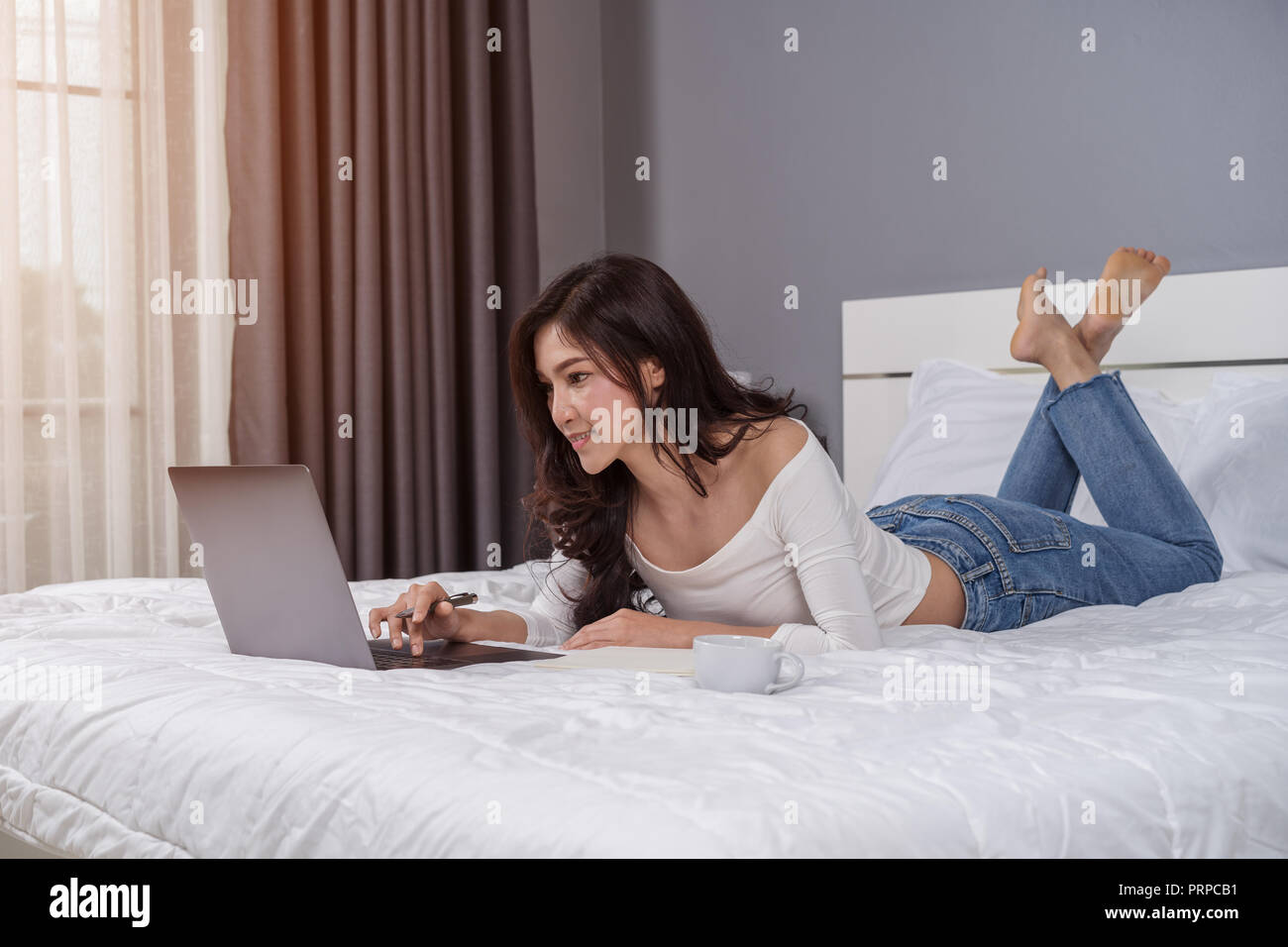 woman working with laptop on a bed Stock Photo - Alamy