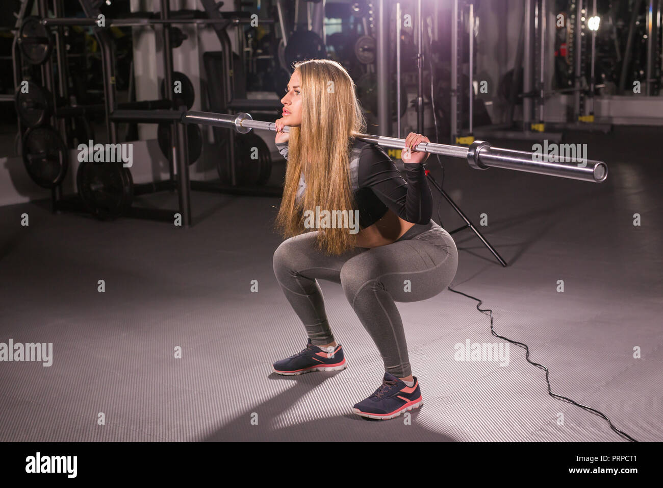 Pretty woman working out with barbell in a gym Stock Photo - Alamy