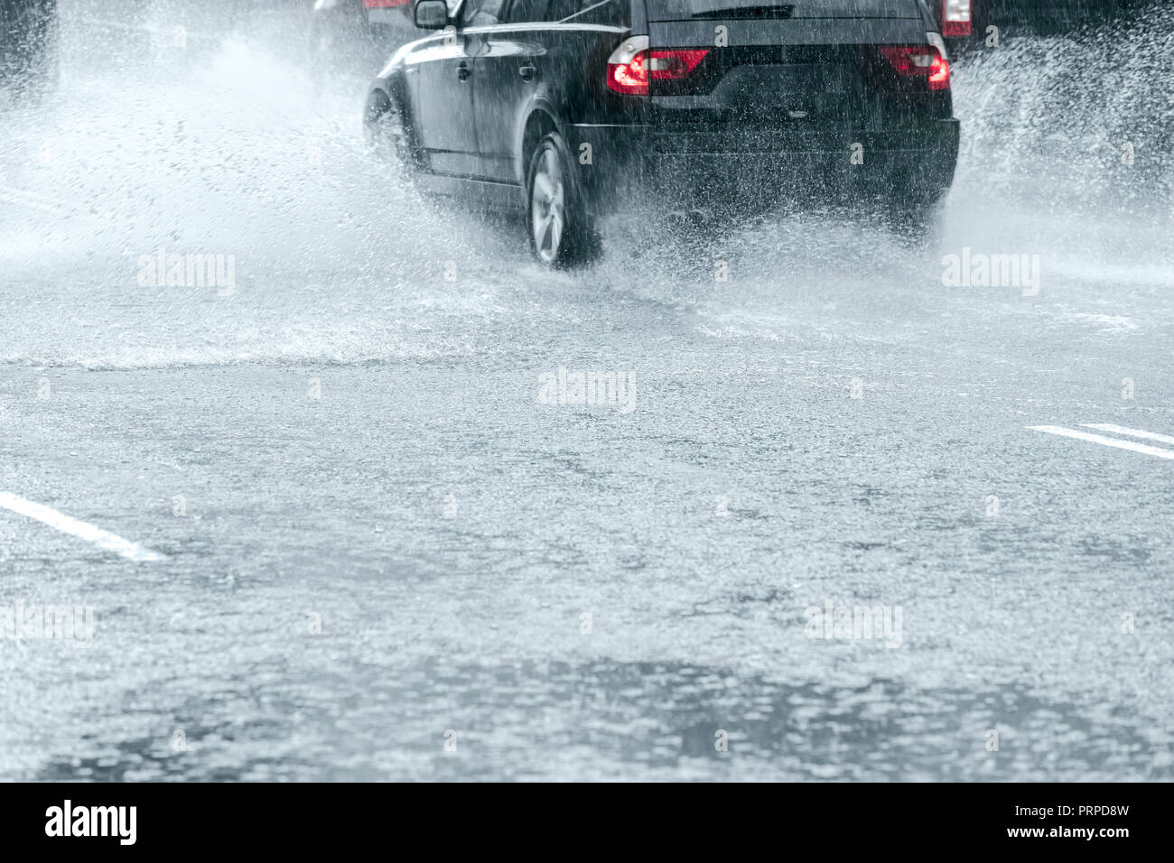 car driving In high speed through big water puddle during heavy rain ...