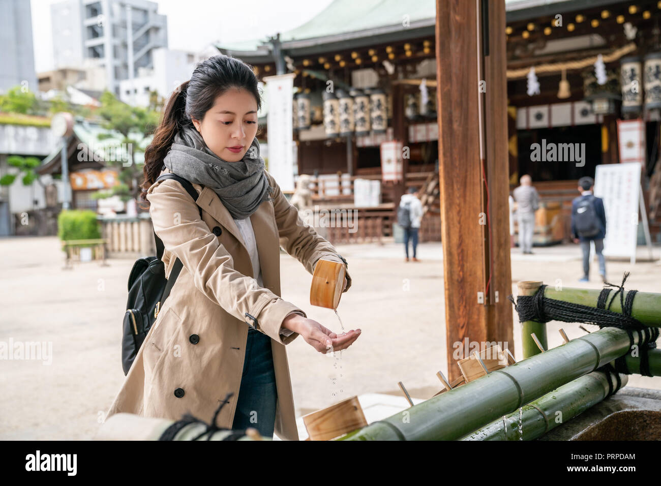 pretty female tourist washing hands in the temple, she is wearing a ...