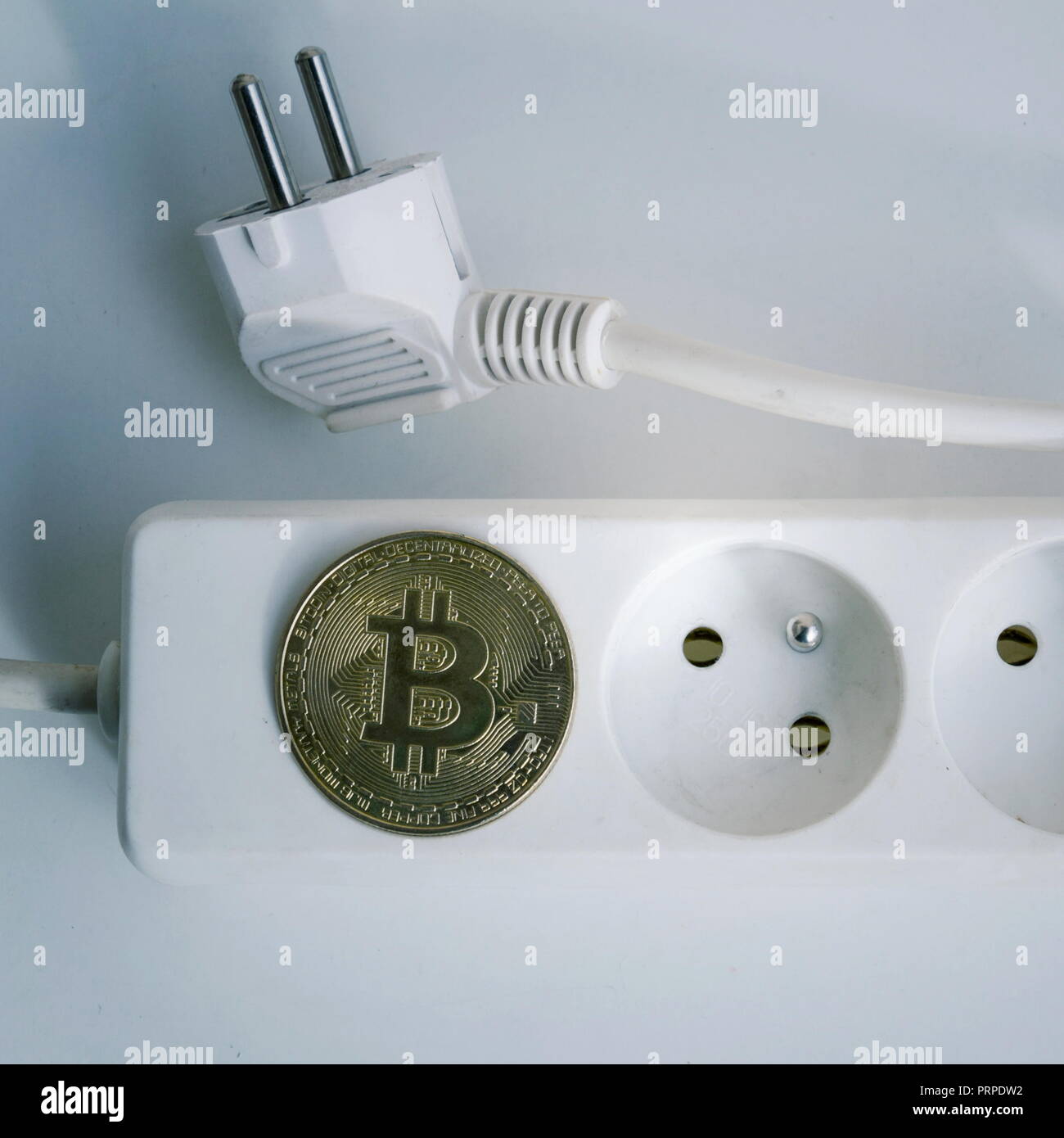 Bitcoin coin lying on power strip extension cord with two empty sockets ...