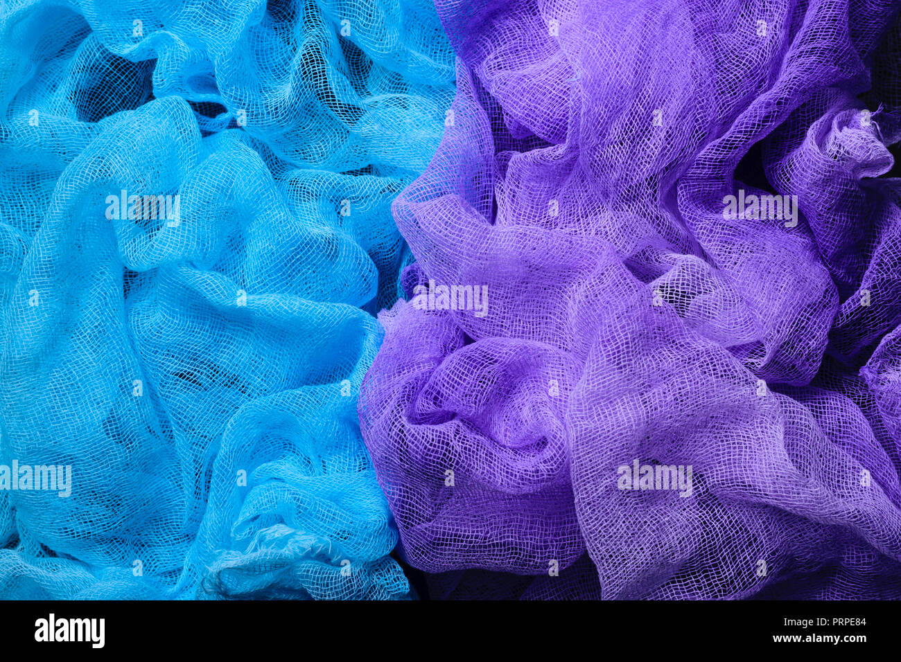 Handmade dyed textured gauze fabric background. Blue and purple colors ...