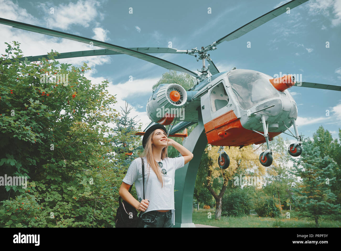 Attractive young girl looking to the sky with a small cute helicopter ...