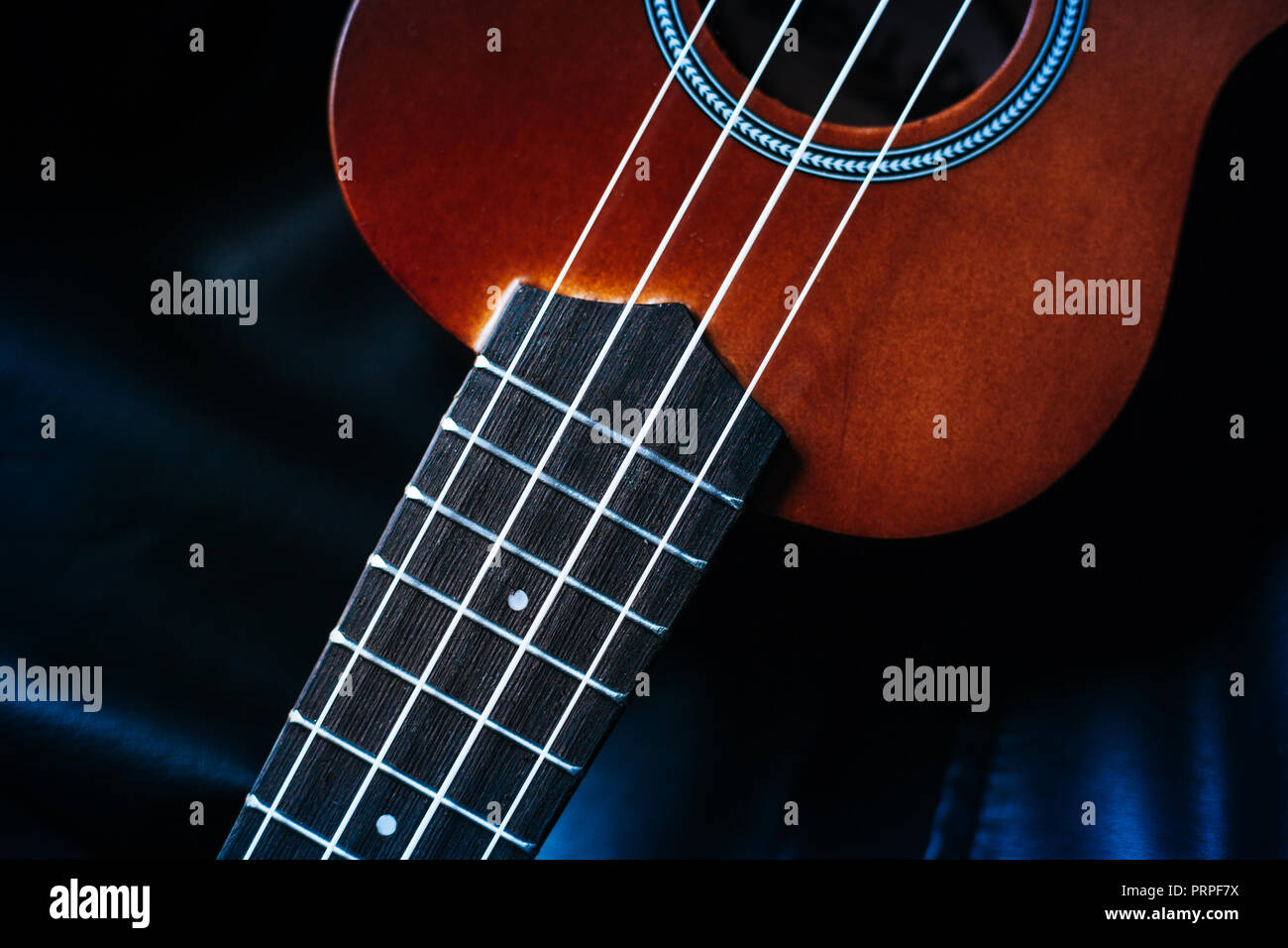 closeup photo of a ukulele against a black leather background Stock ...