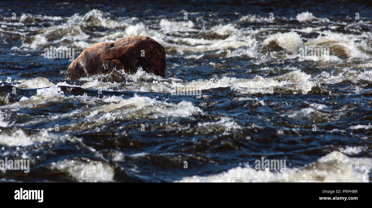Huge block, stone in a river. Water in speed all around. The block ...
