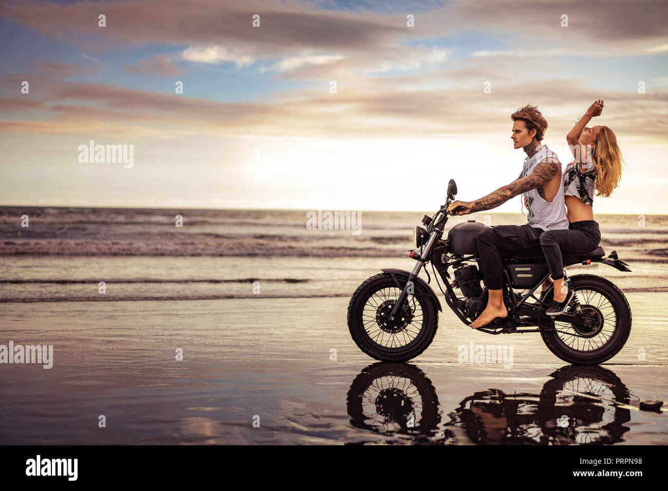 side view of couple riding motorcycle on ocean beach Stock Photo - Alamy