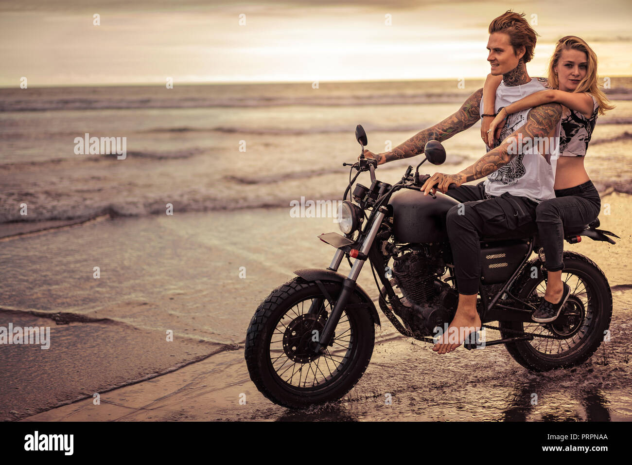 passionate couple riding motorcycle on ocean beach during sunrise Stock ...
