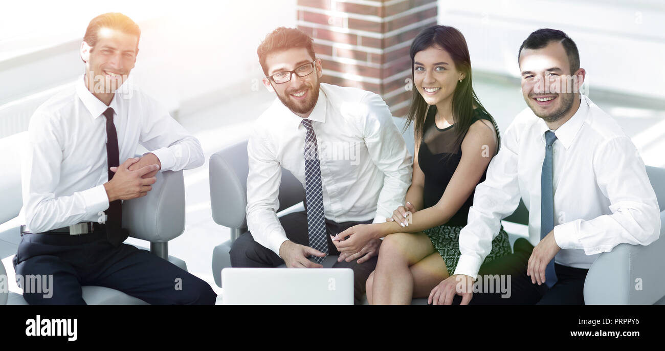 successful business team sitting in office lobby, in front of an open ...