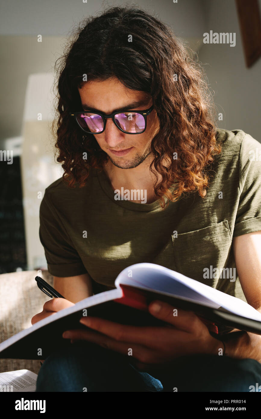 Student studying at home making notes in a book. Student studying with ...
