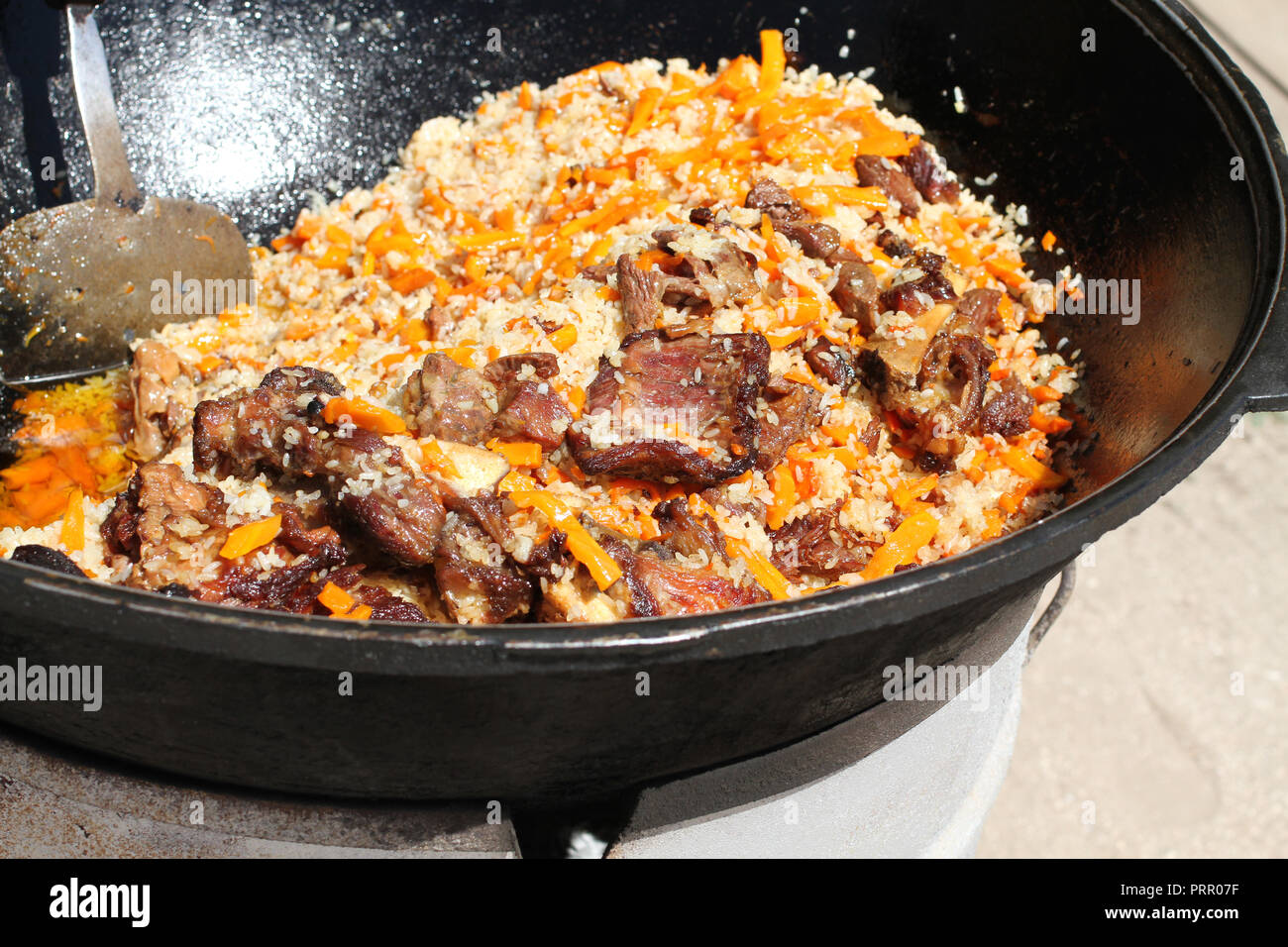 Traditional Uzbek pilaf with lamb meat cooked in a large cauldron Stock ...