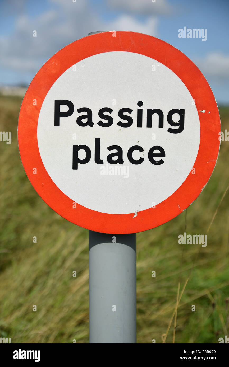 Passing place road sign with black text in a red circle with grass and ...
