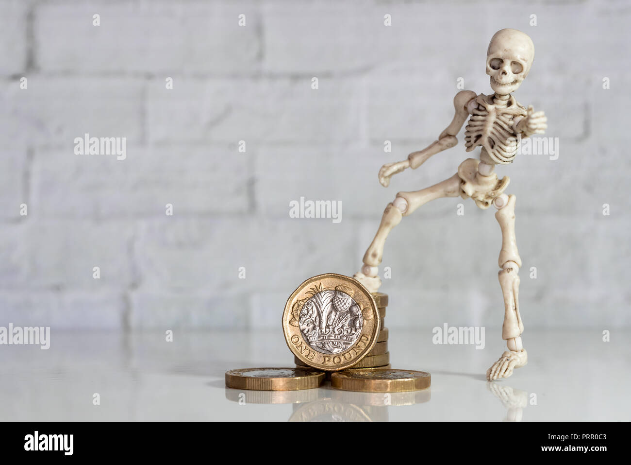 Skeleton standing on pound coins Stock Photo - Alamy