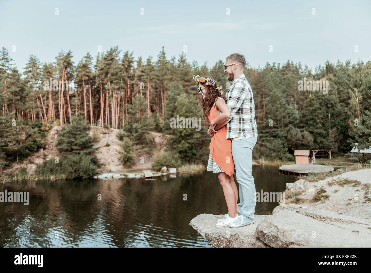 Cute happy loving couple having rest near big beautiful lake and rocks ...
