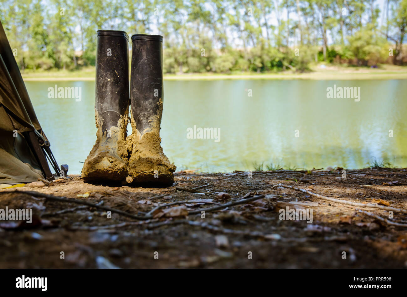 dirty boots standing next to the fishing tent by the river Stock Photo ...