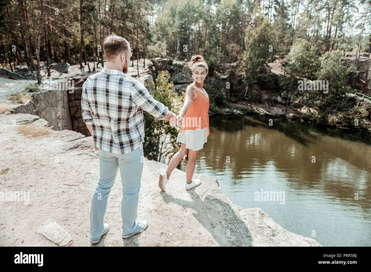 Strong supportive man holding hand of his beaming girlfriend coming ...
