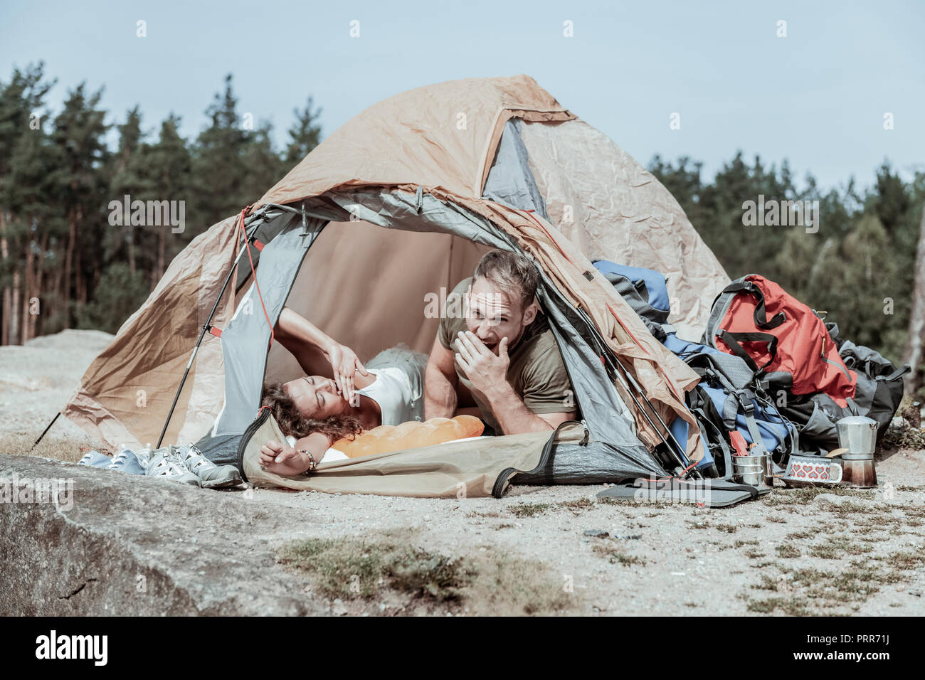 Two backpackers yawning together while waking up in their tent in ...