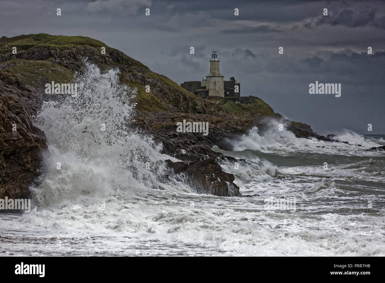 Waves crash against rocks by Mumbles lighthouse in Bracelet Bay ...