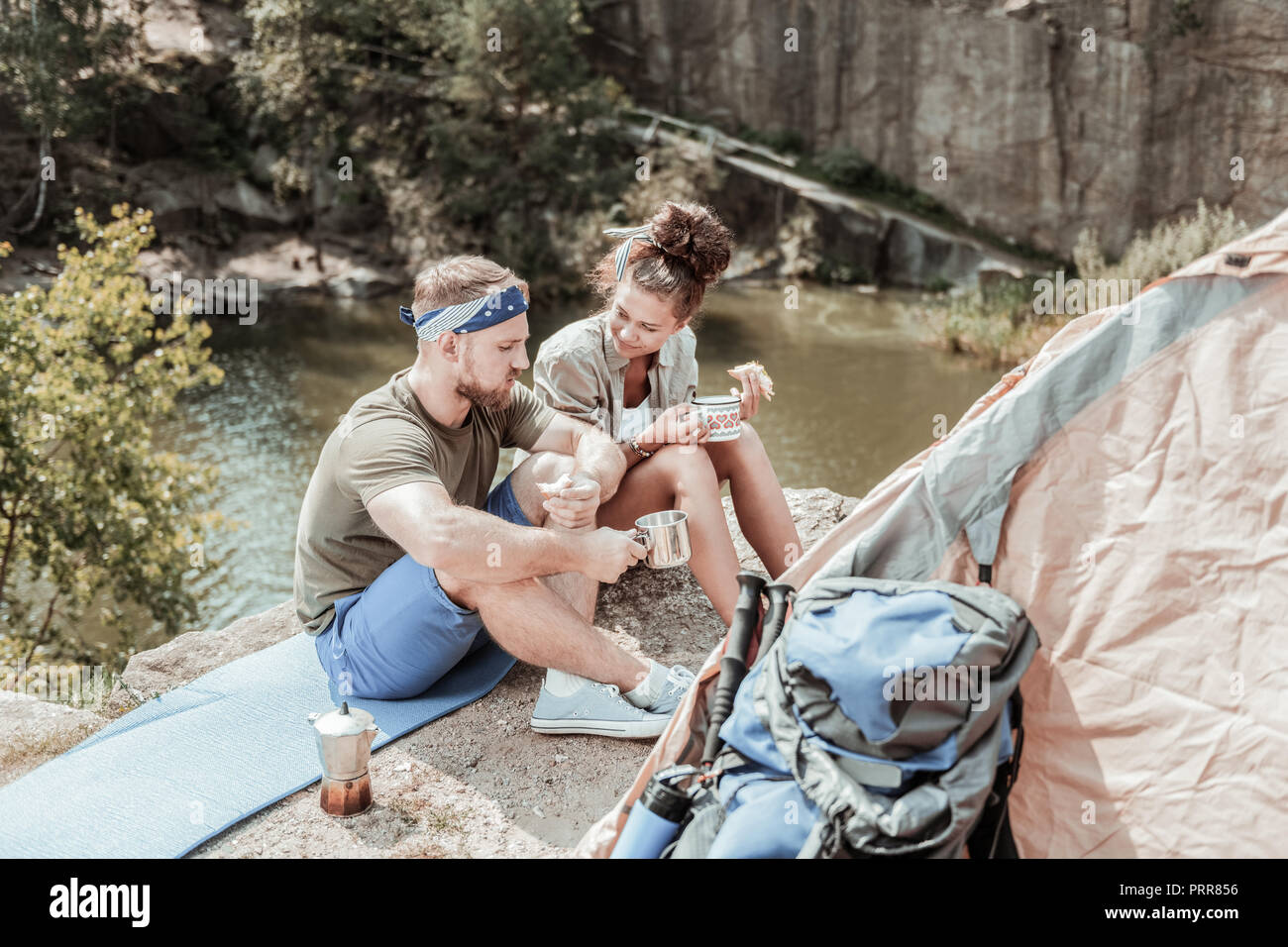 Couple of active hikers enjoying their breakfast after night in tent ...