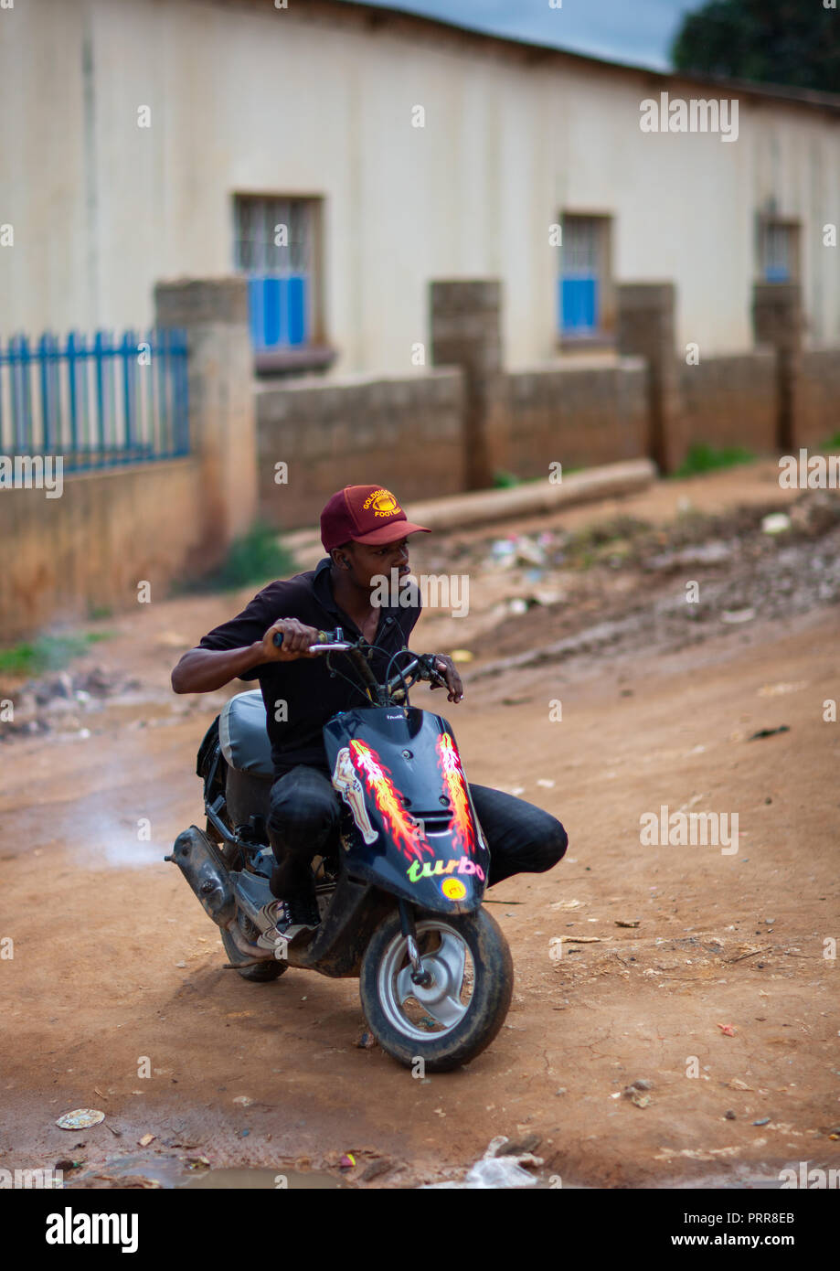 Angolan young man driving a scooter in the street, Huambo Province ...