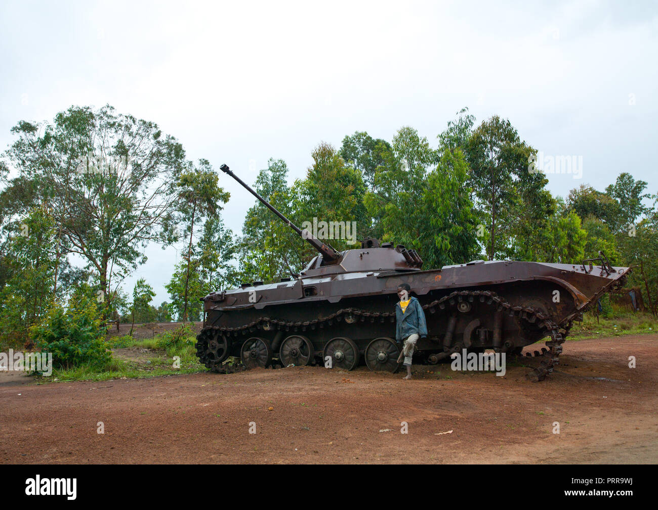 Angolan child standing in front of an old tank from the civil war, Bié ...