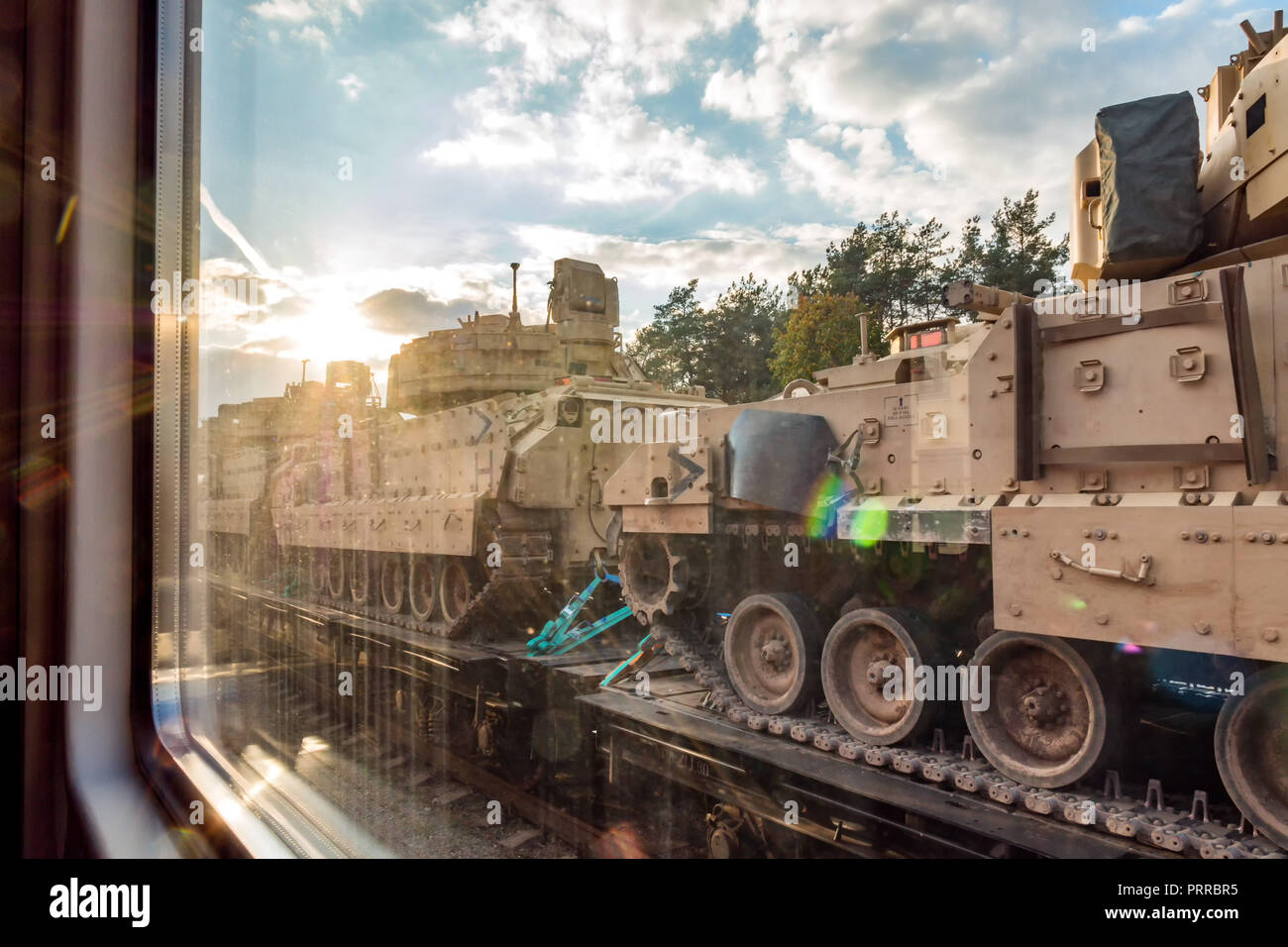 Sunny day view of US american tanks loaded on train through train ...