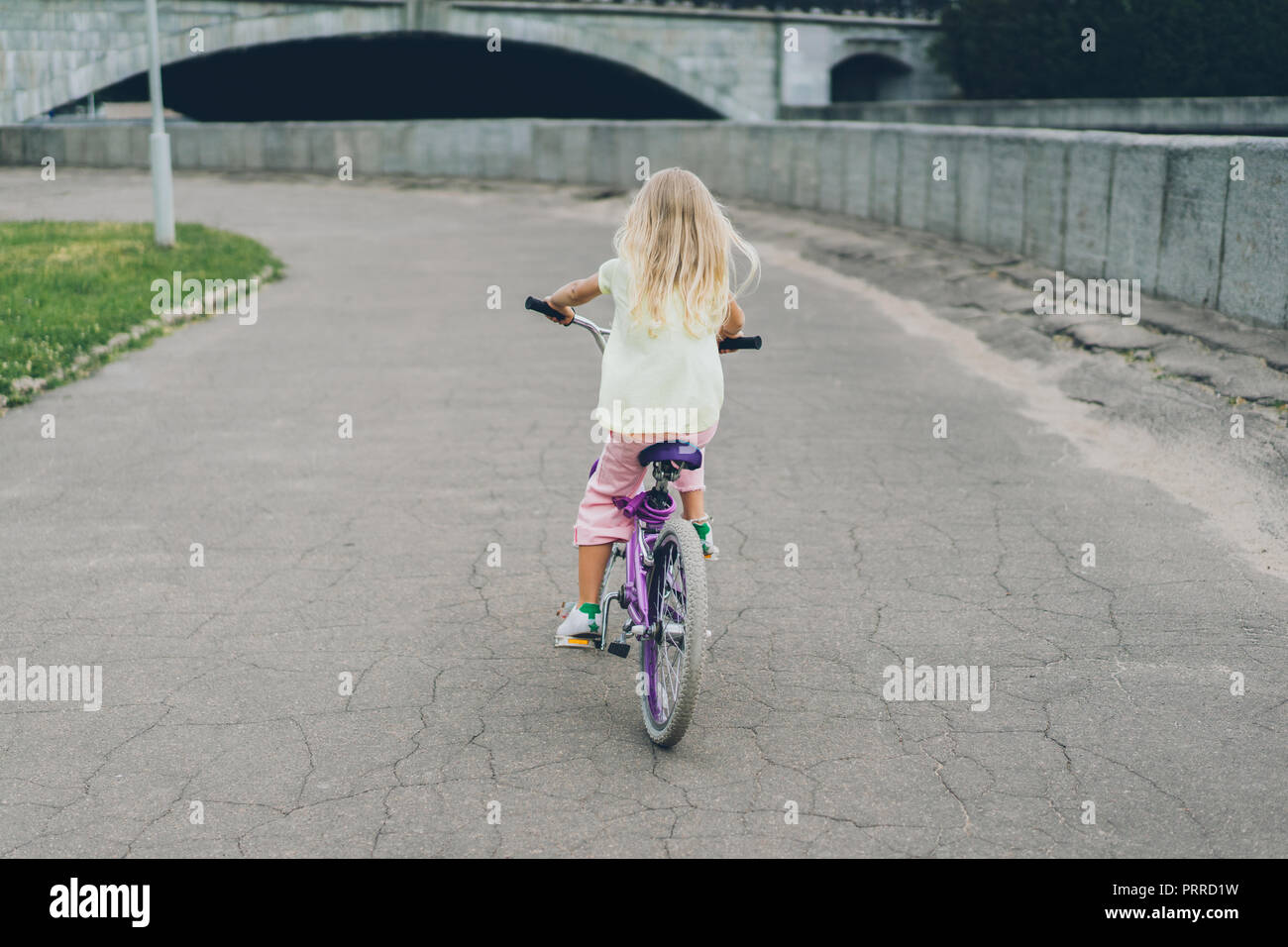back view of blond child riding bicycle on street Stock Photo - Alamy