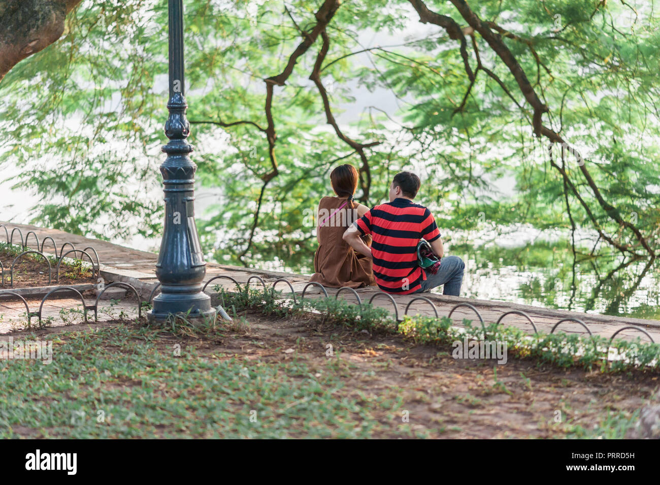Young couple relaxing on the waterfront of the Sword Lake at sunset. Romantic afternoon outing ...