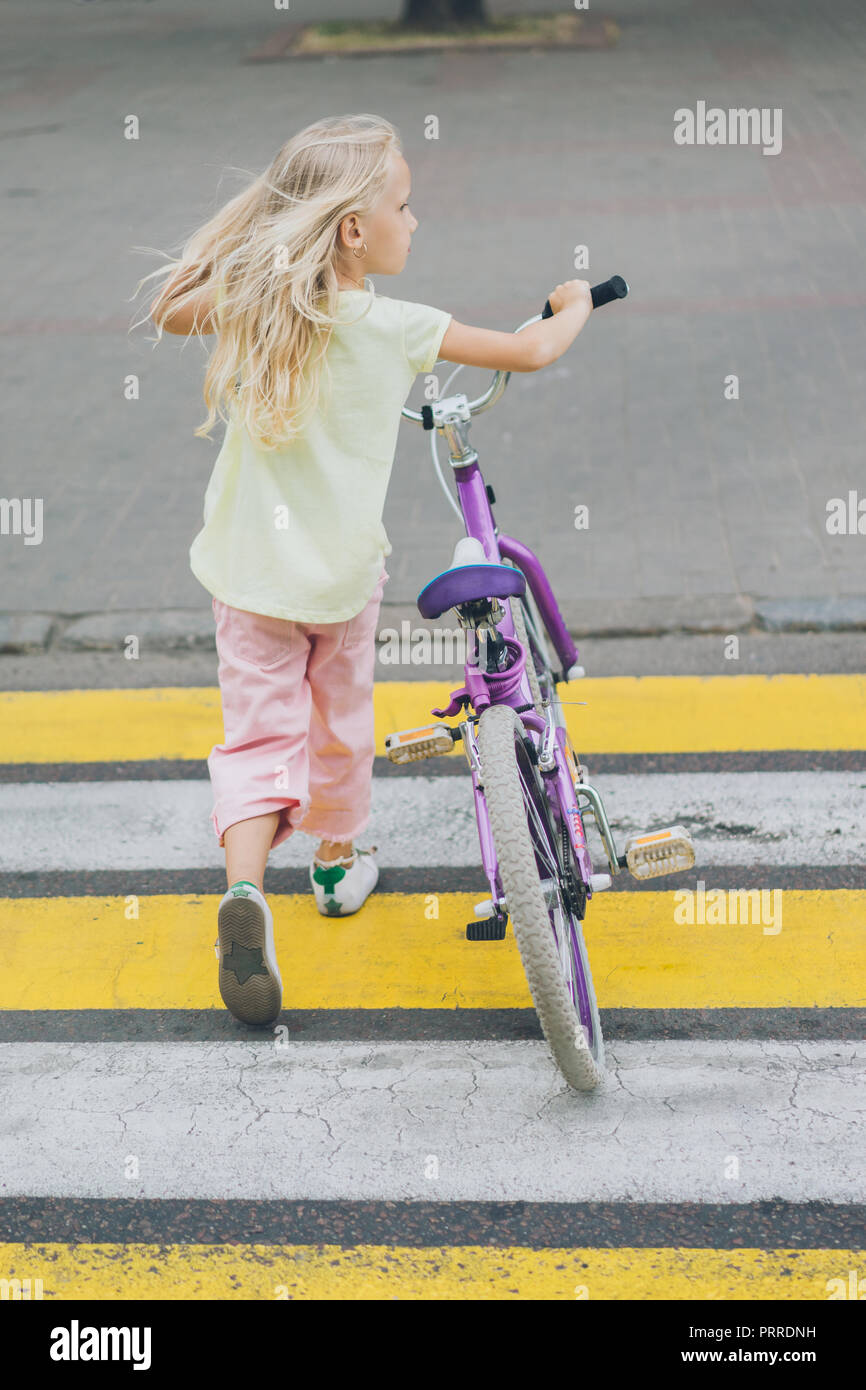 back view of little kid with bicycle crossing road Stock Photo - Alamy