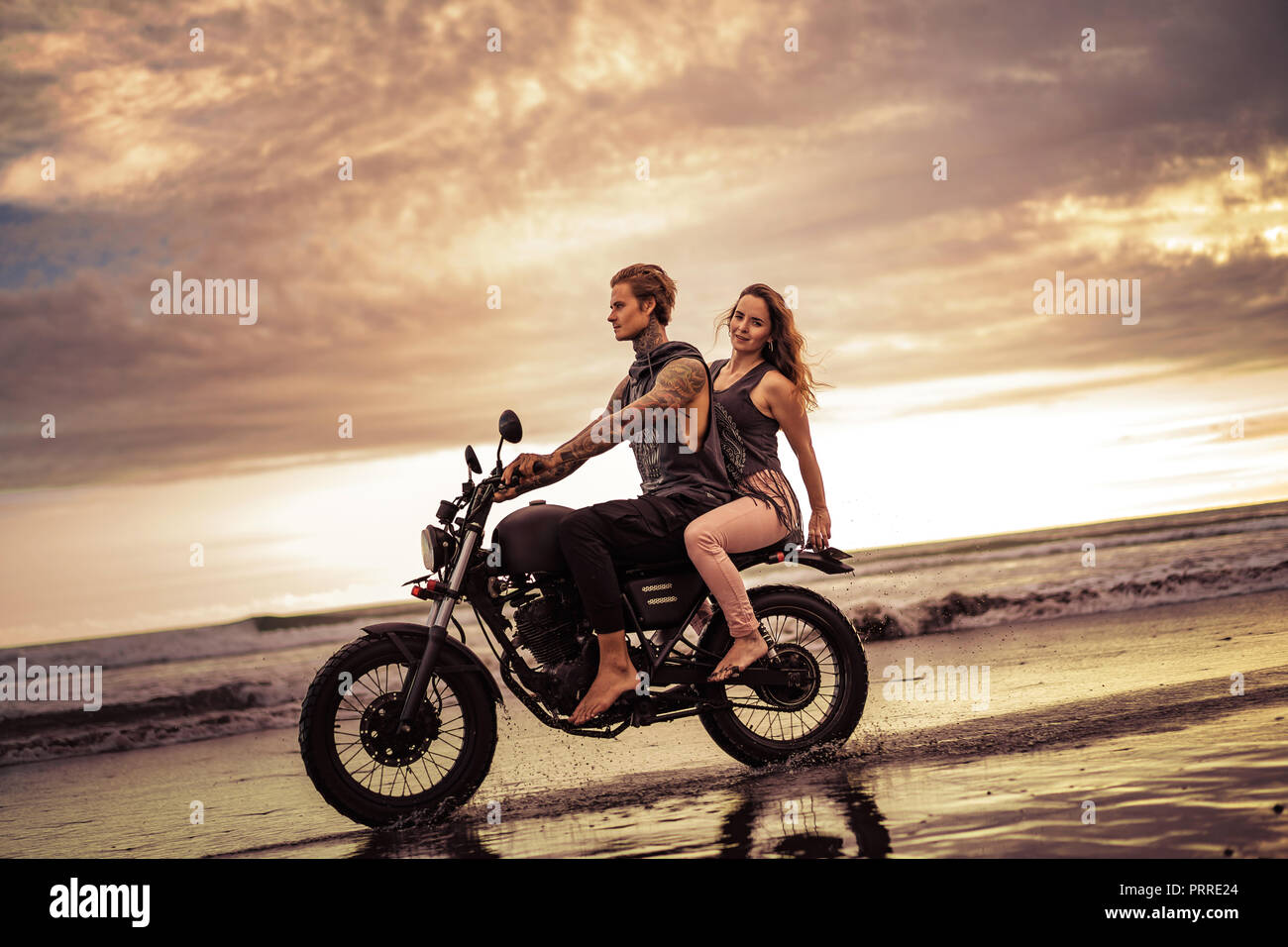couple riding motorcycle on ocean beach in morning Stock Photo - Alamy